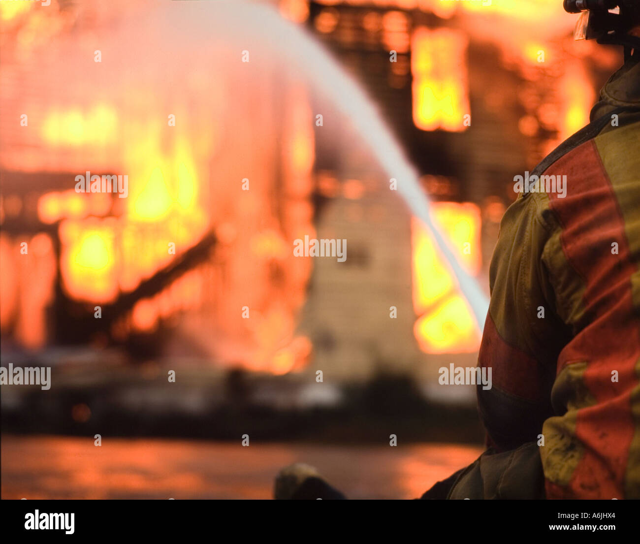 Fire fighter sitting spraying water on burning house Stock Photo - Alamy