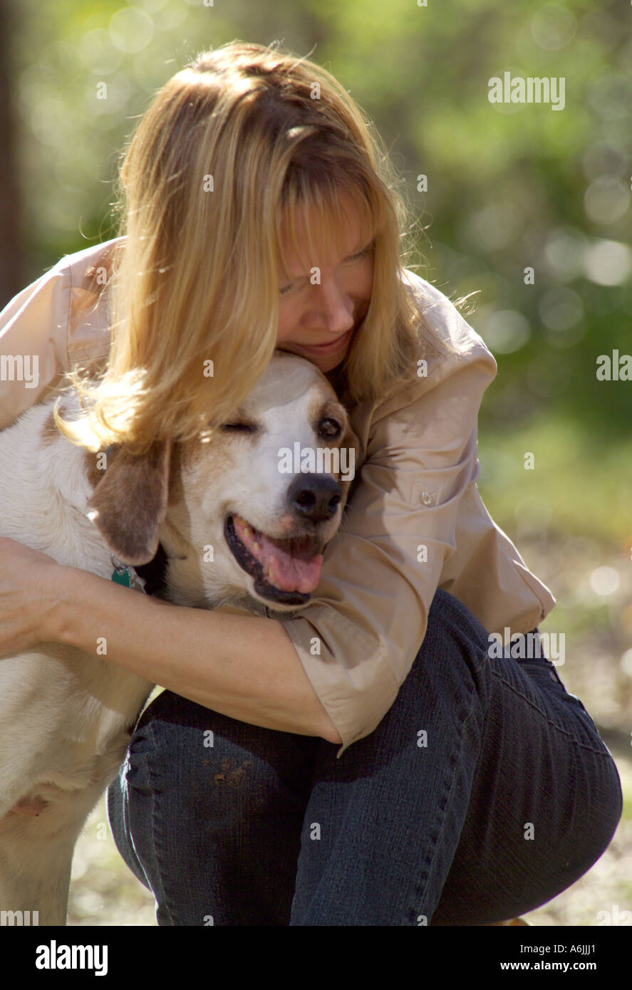 Mature woman hugs hound dog who appears to be winking at us Stock Photo ...