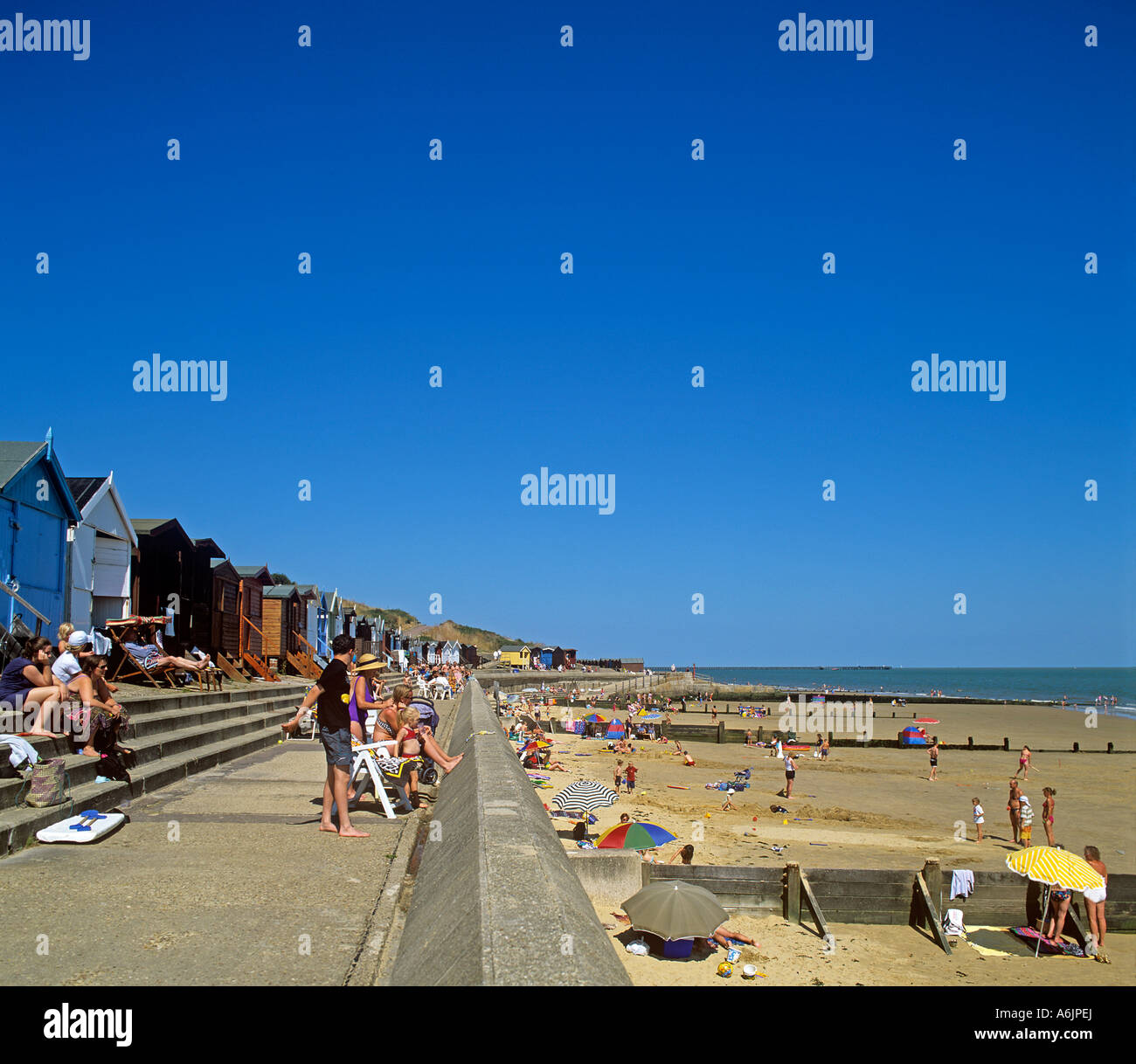 Frinton beach huts behind the promenade along the wide sandy beach ...