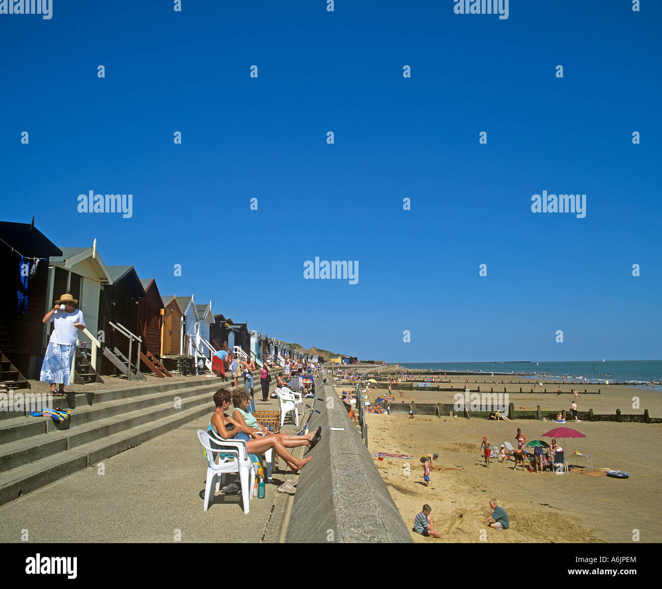 Frinton beach huts behind the promenade along the wide sandy beach ...