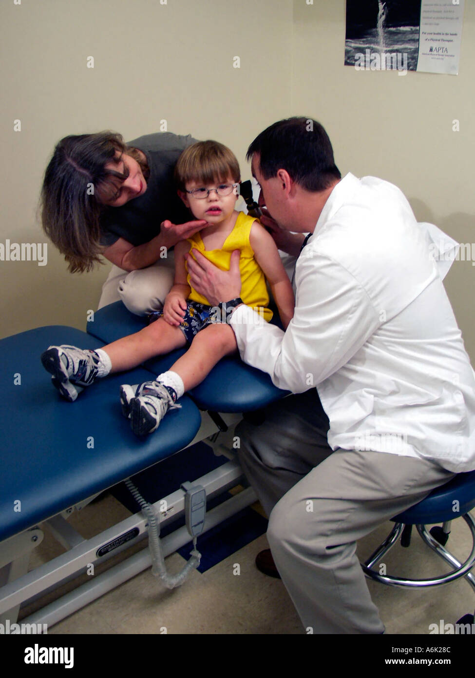Young boy havng his ears checked by a doctor during a physical exam ...