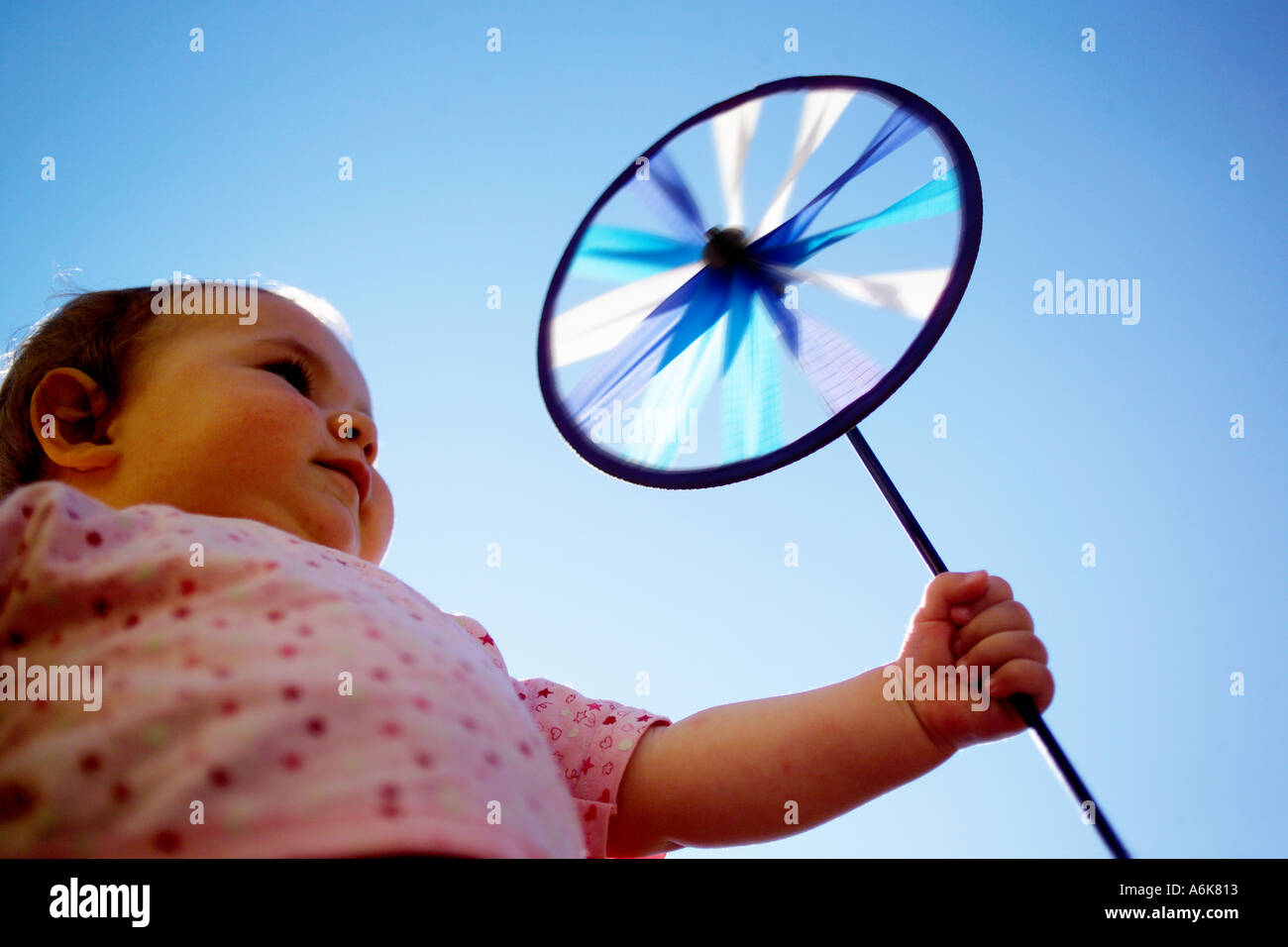 little baby holding a windwheel up in the sky Stock Photo - Alamy