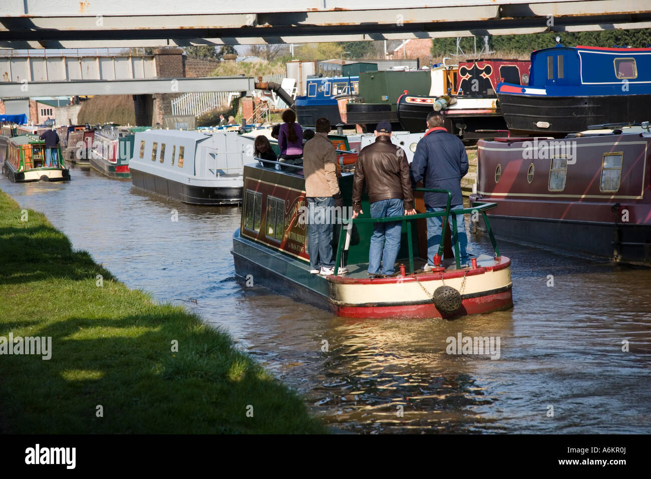 Holidaymaker s narrow boat passes a boatyard on the Trent Mersey Canal ...