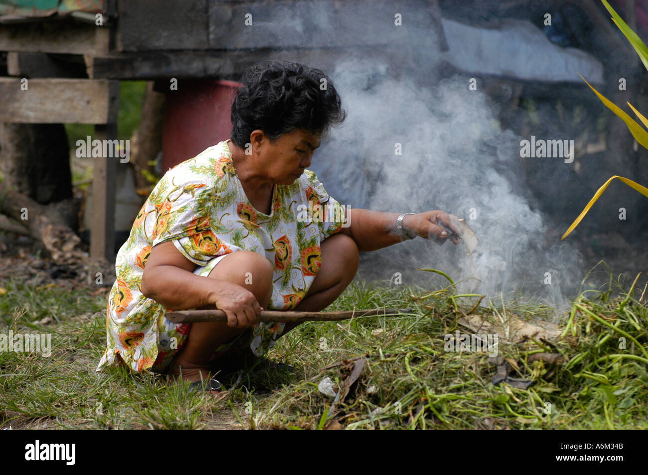 Wooman burning something by the side of the road Bohol Stock Photo - Alamy
