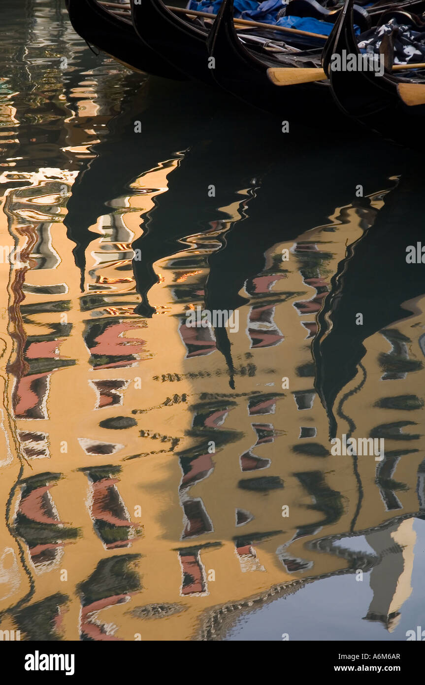 Reflection in the water of ochre buildings and gondolas in Venice ...