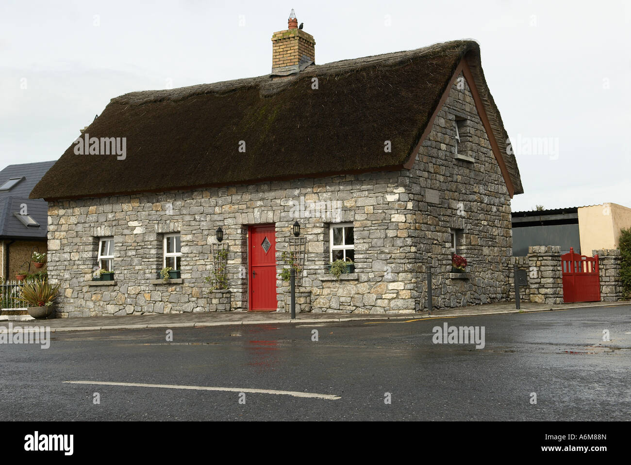 Classic stone house with a thatched roof and red door and gate in ...