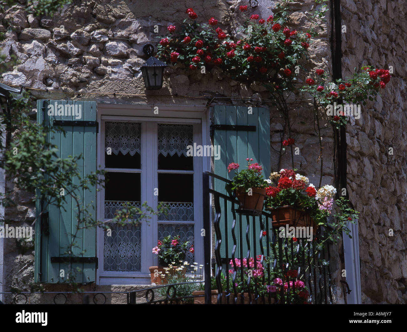 Traditional house with window shutters, balcony and flower baskets ...