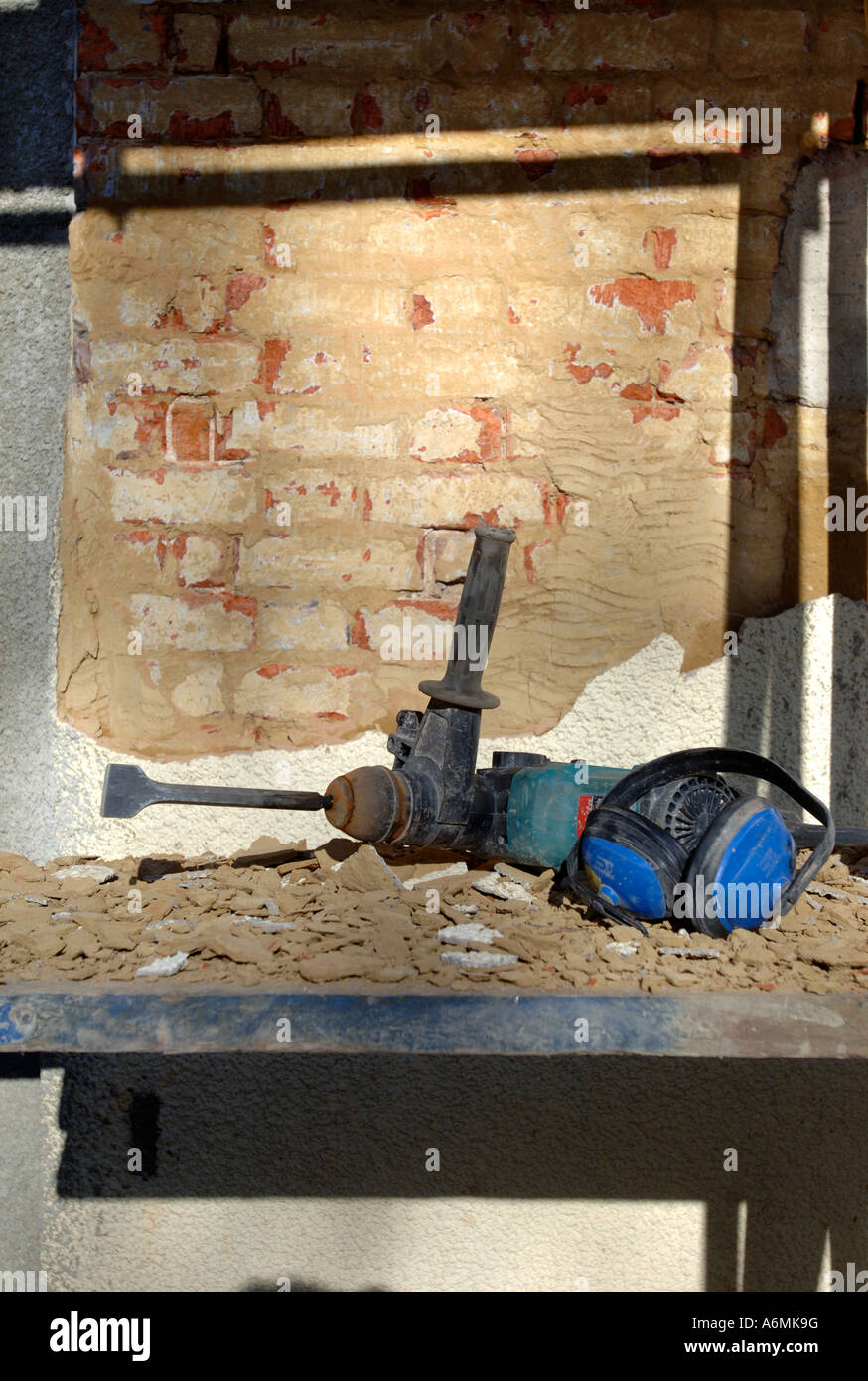 A BREAKER MACHINE USED TO REMOVE OLD RENDERING FROM A RED BRICK WALL ON ...