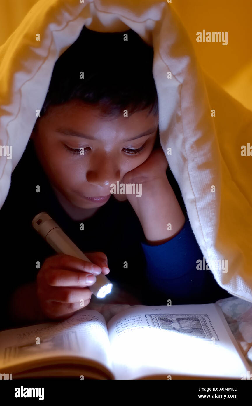 Boy reading with flashlight under sheets Stock Photo - Alamy
