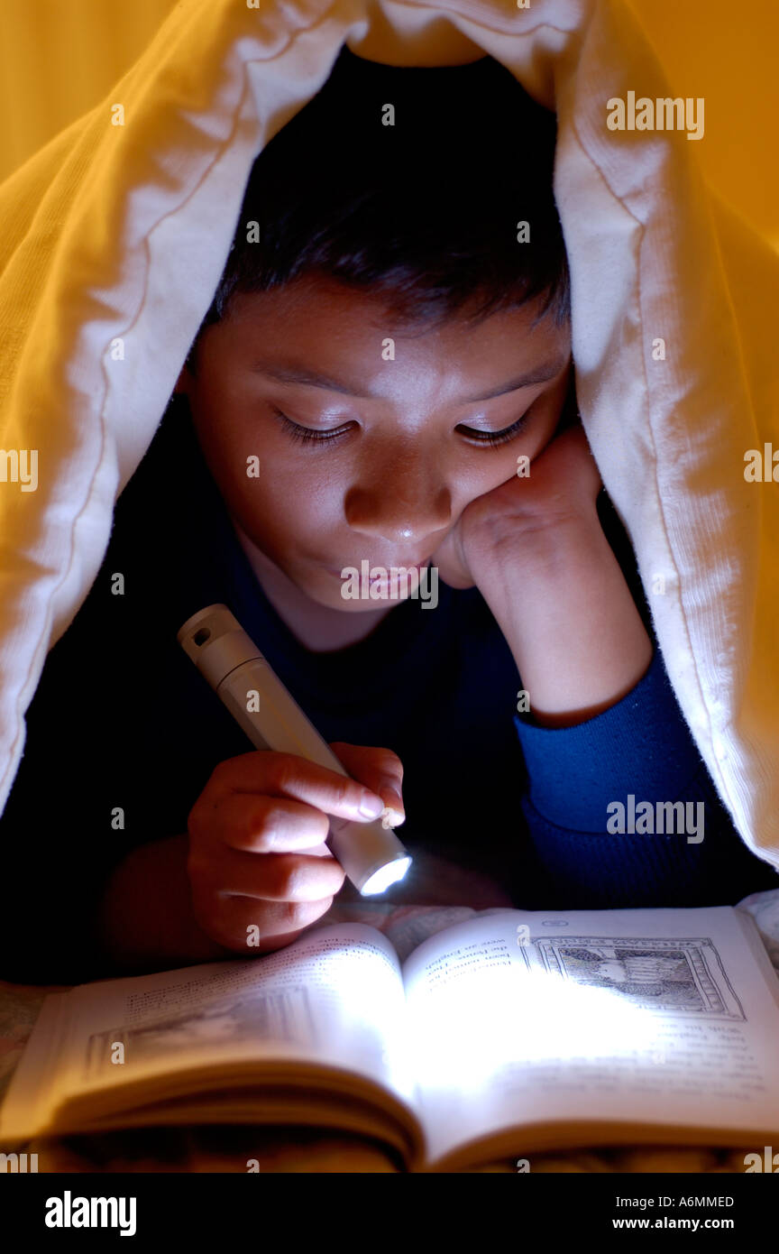 Boy reading with flashlight under sheets Stock Photo - Alamy