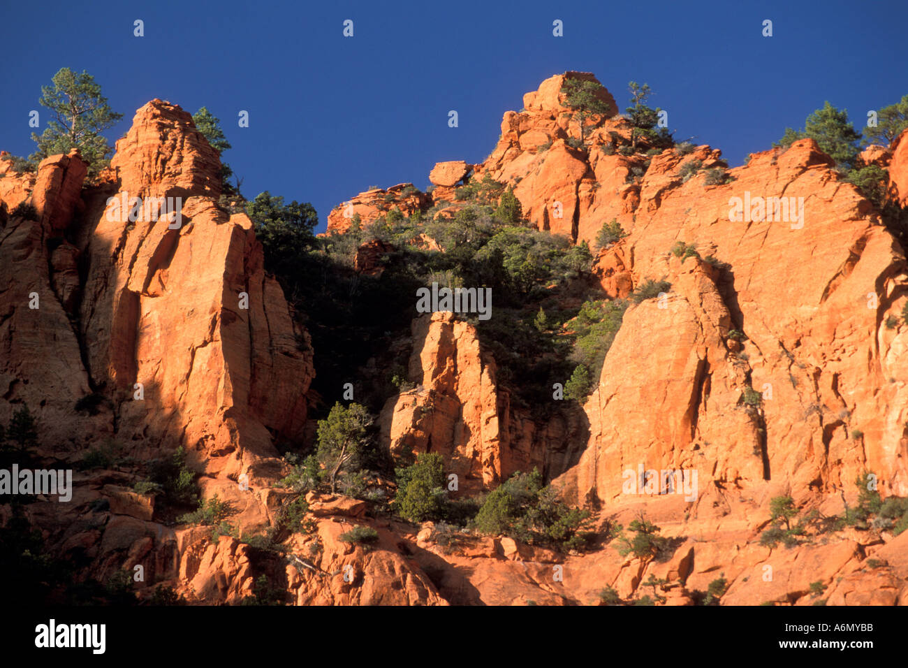 Golden sunset light on red sandstone peaks and sheer rock cliffs in the ...