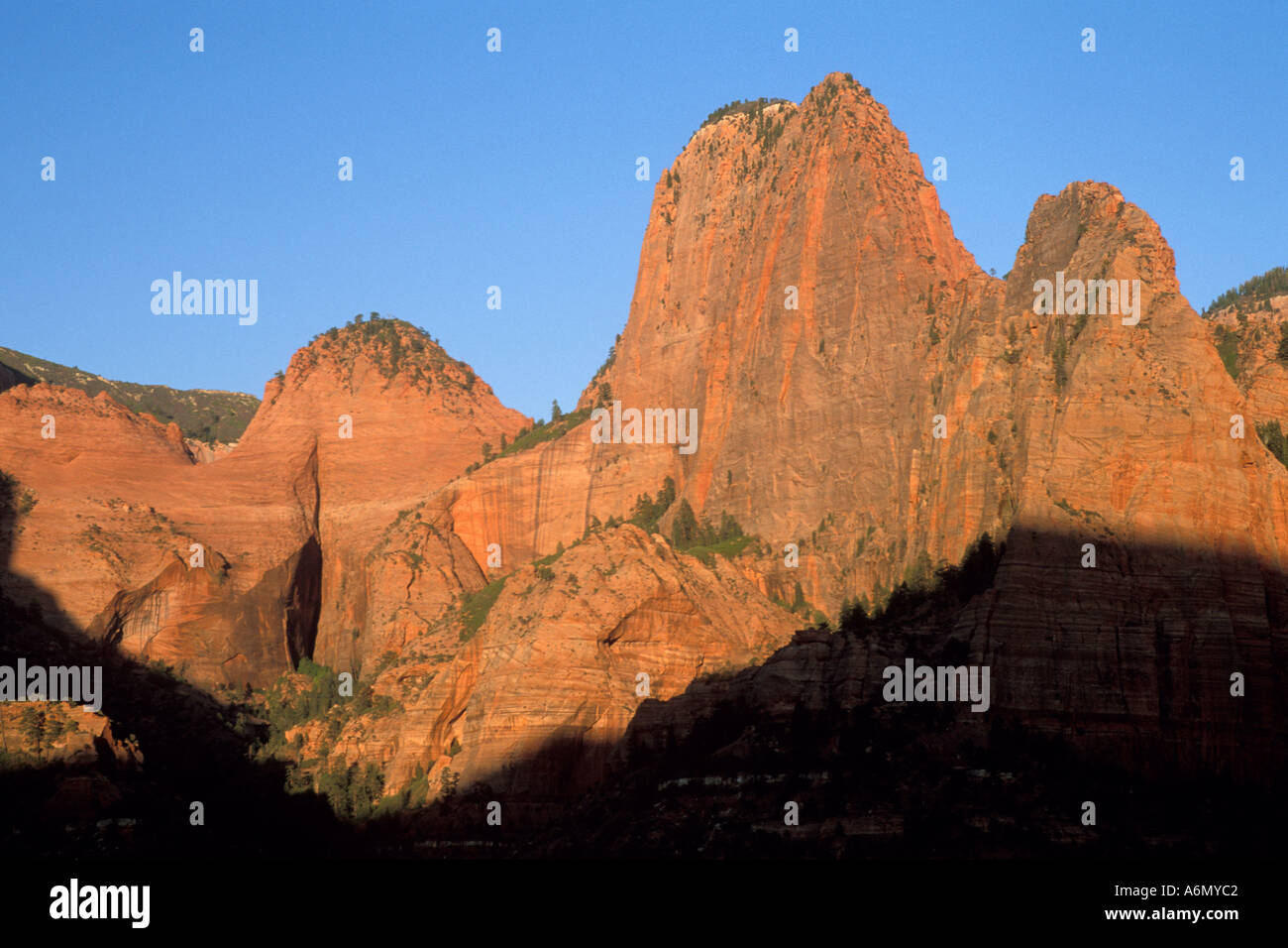 Golden sunset light on red sandstone peaks and sheer rock cliffs in the ...