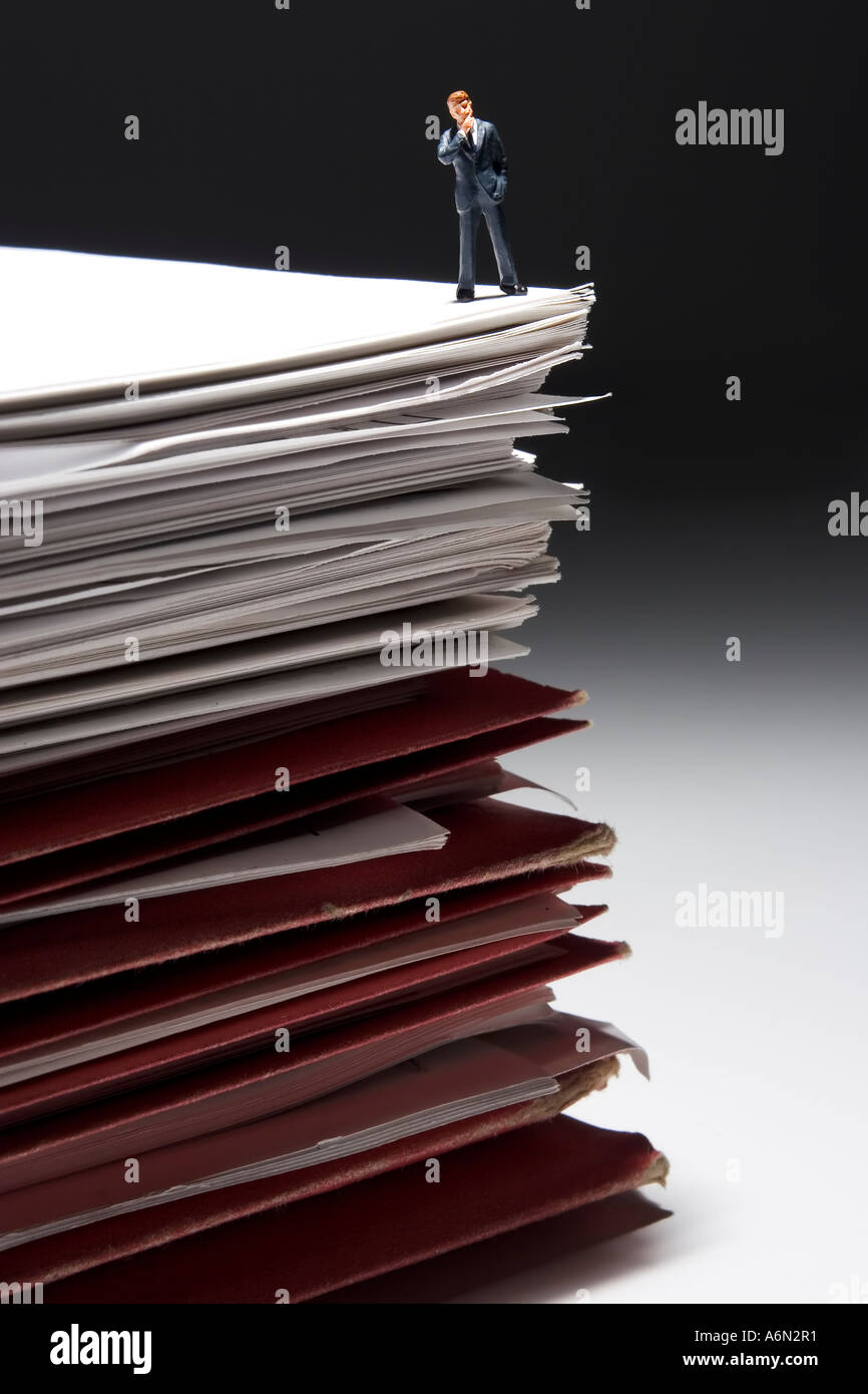 Business figure on a stack of papers and folders Stock Photo - Alamy