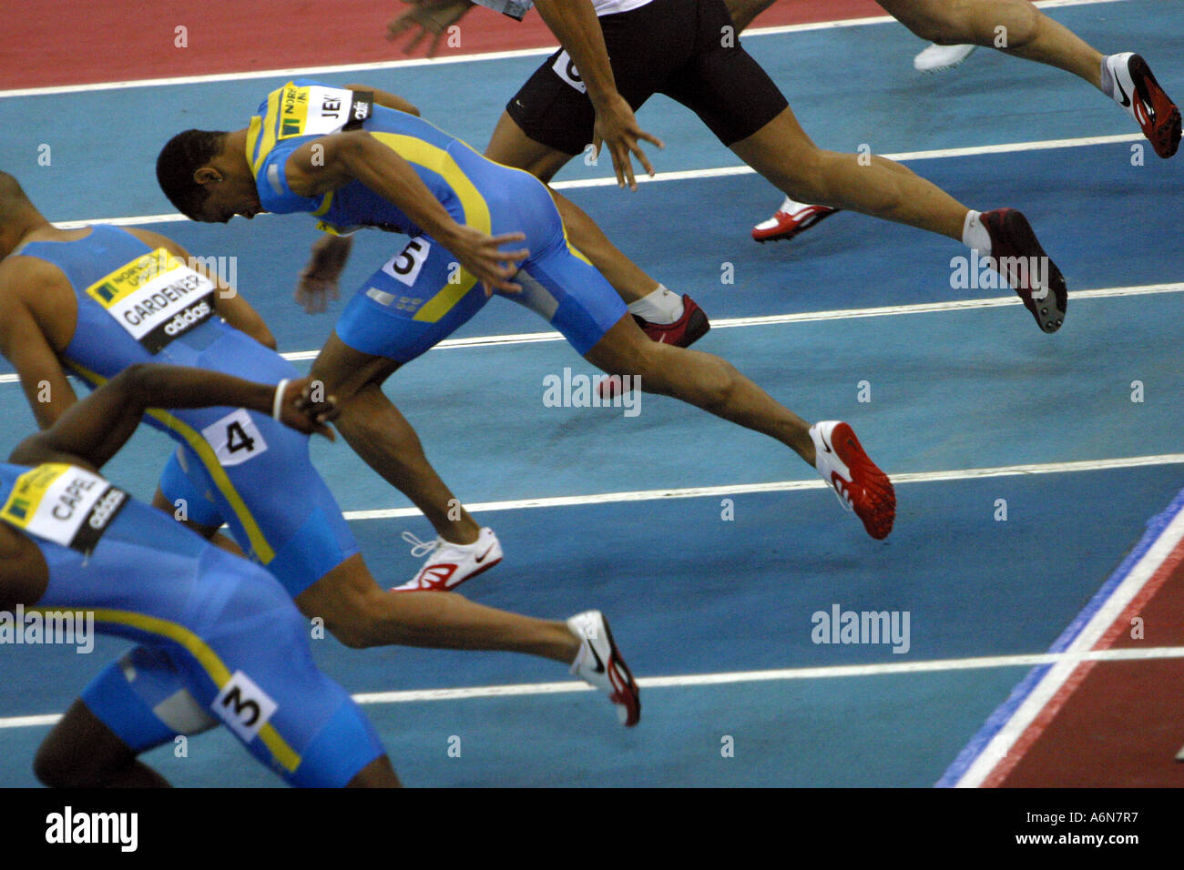 Male runners explode from the starting blocks in a indoor sprint ...