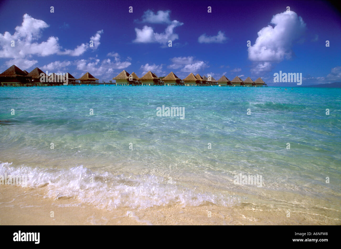 Thatched roof bungalows on horizon of crystal clear lagoon Stock Photo ...