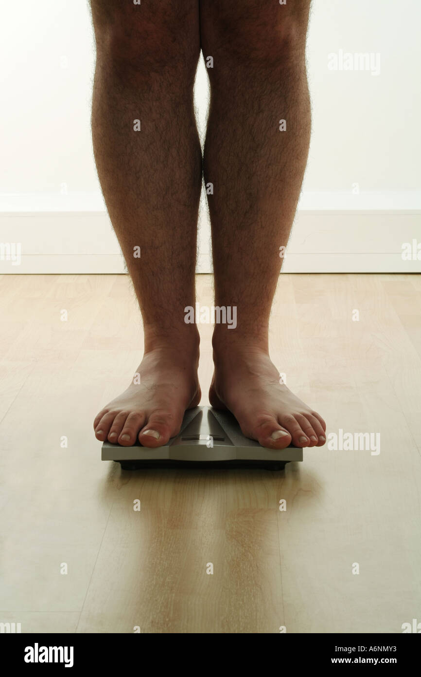 Man on scales checking weight Stock Photo - Alamy