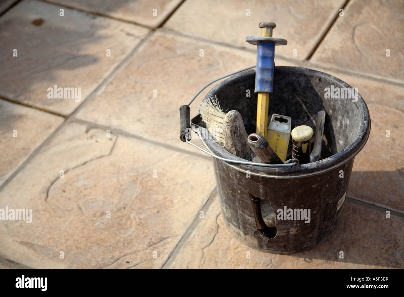 Sundry builders tools in a bucket on paved area Stock Photo - Alamy