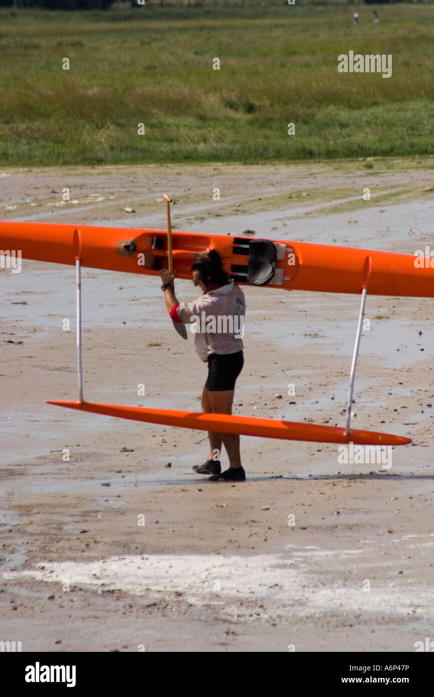 Man carrying outrigger canoe back up beach from river Saint Valery sur ...