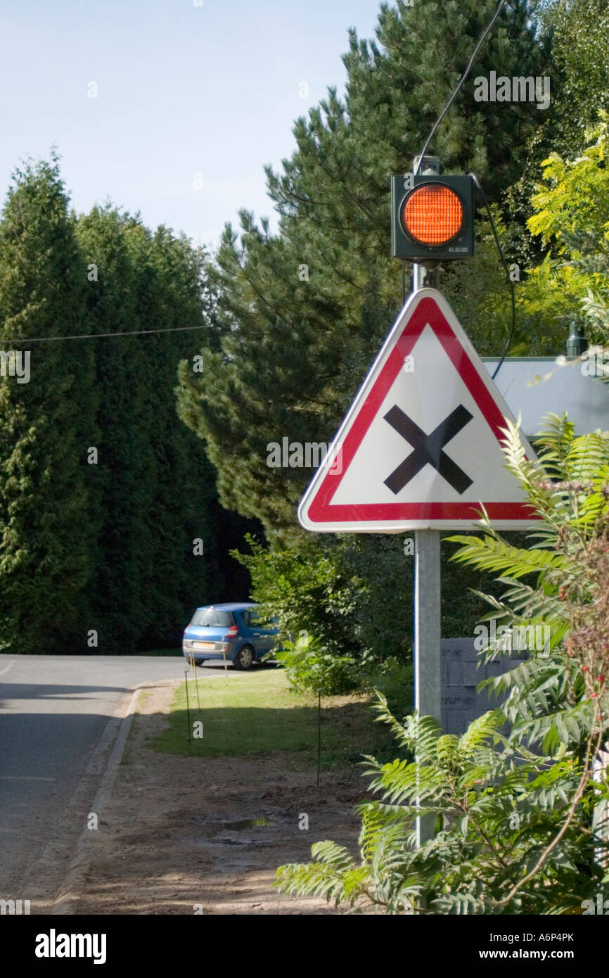 Crossroads sign with amber light flashing on aproach to road junction ...