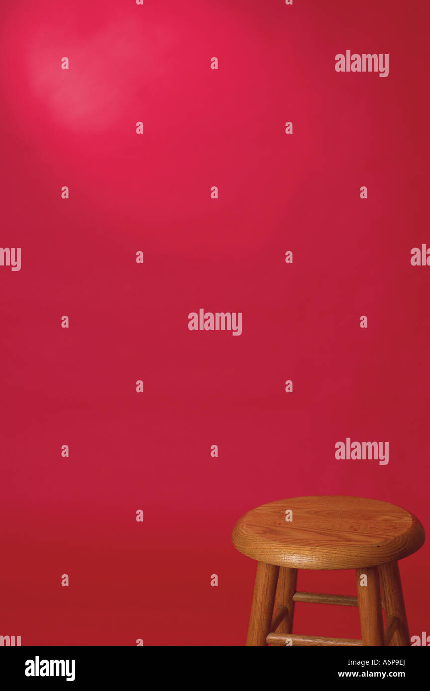 An empty bar stool sits against a bright red background Stock Photo - Alamy