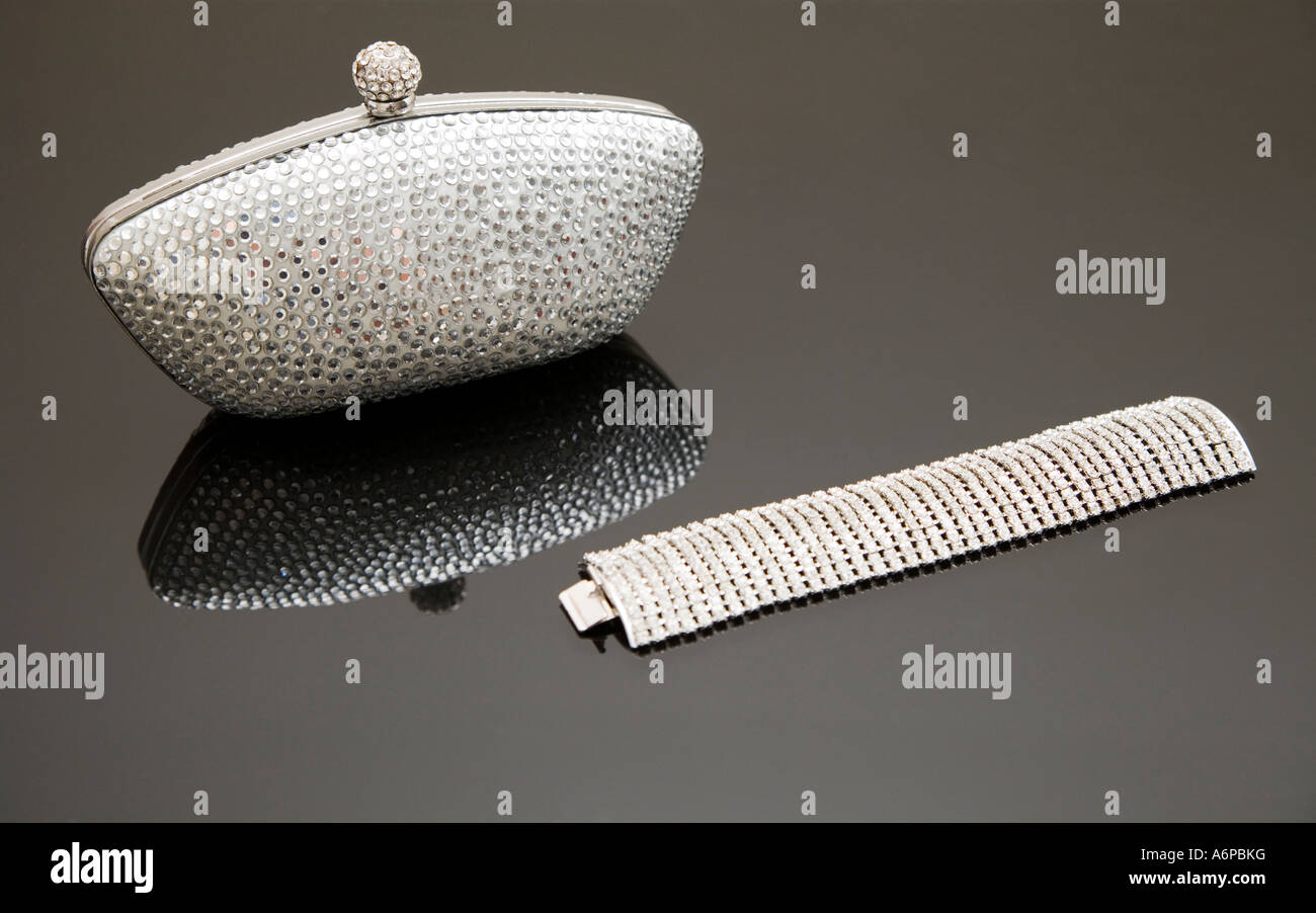 Very stylish Art Deco silver purse and bracelet on a mirrored surface ...