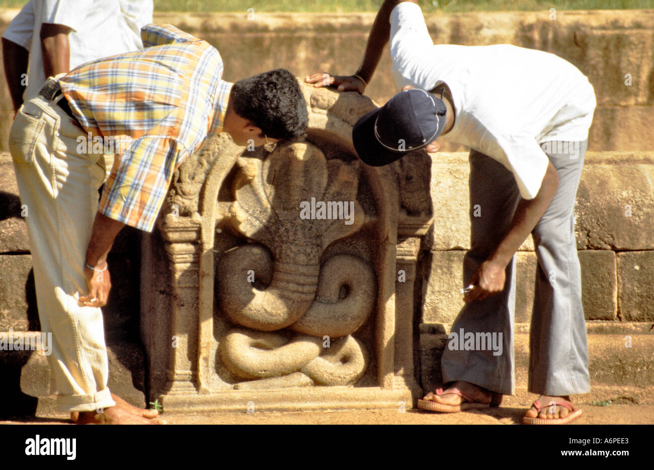 Young men perch on a ledge over a tank at Anuradhapura to inspect a ...