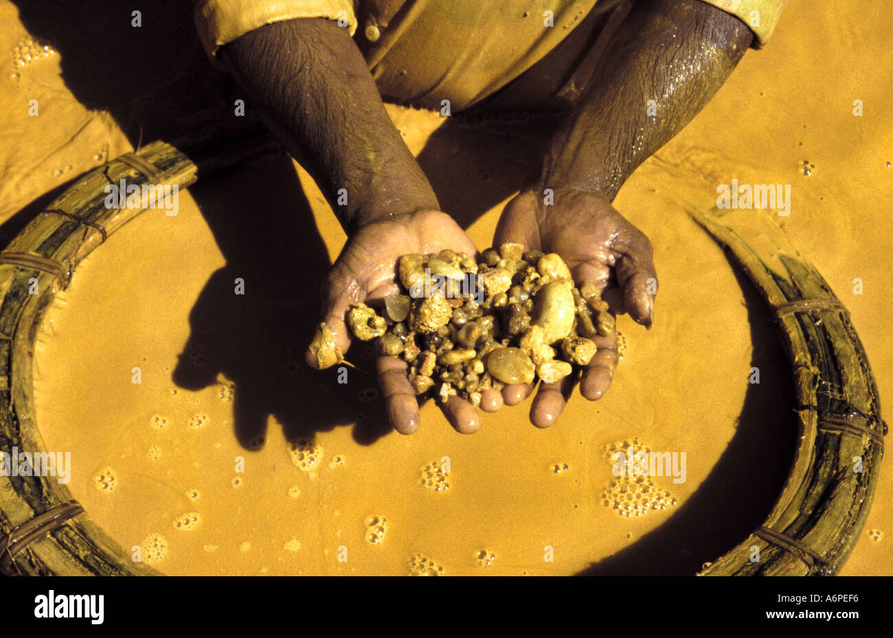 A gem miner shows the product of his work washing stones from mud near ...