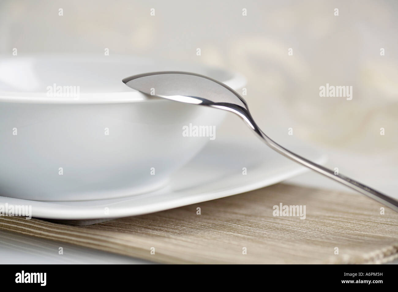 Soup plate with spoon on setting utensil Stock Photo - Alamy