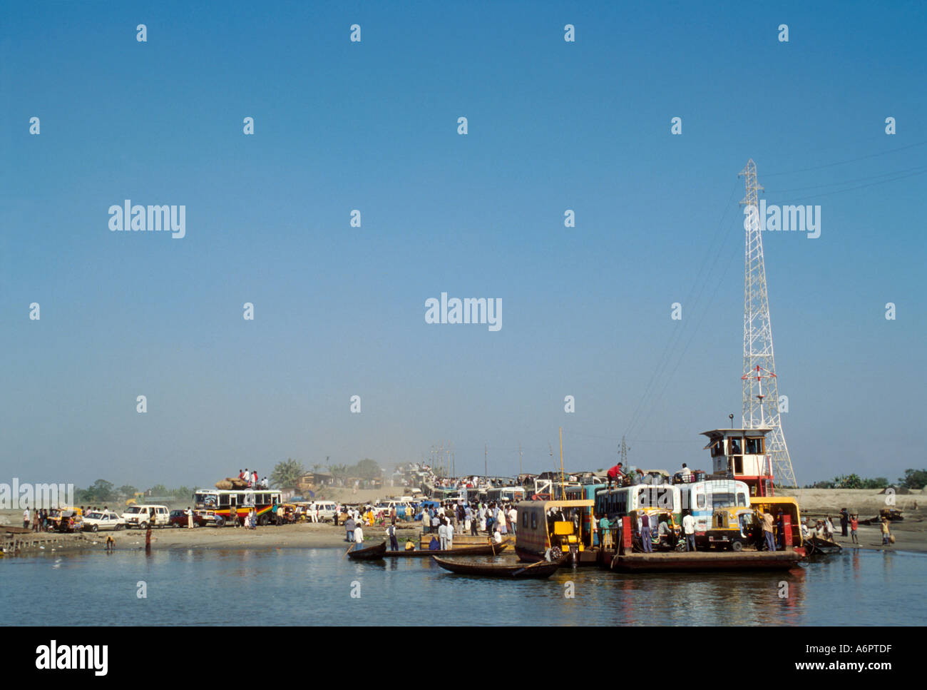 A crowded river ferry with passengers and vehicles landing at the river ...