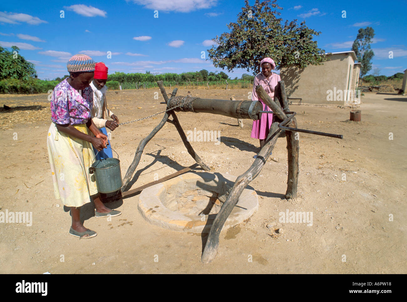 Village women drawing water at an old community windlass well ...