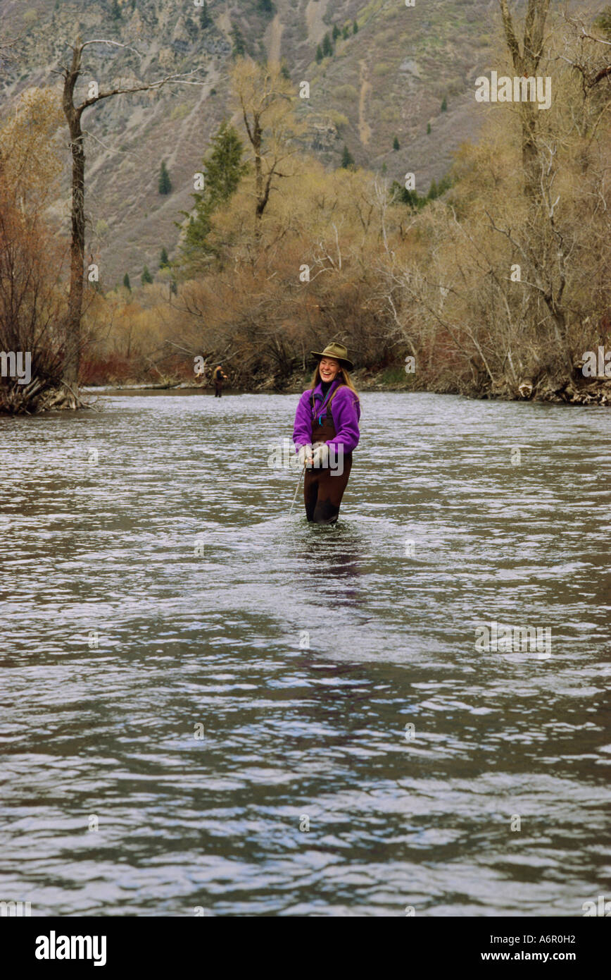 Woman fly fishing standing in the water wearing a purple jacket Stock ...