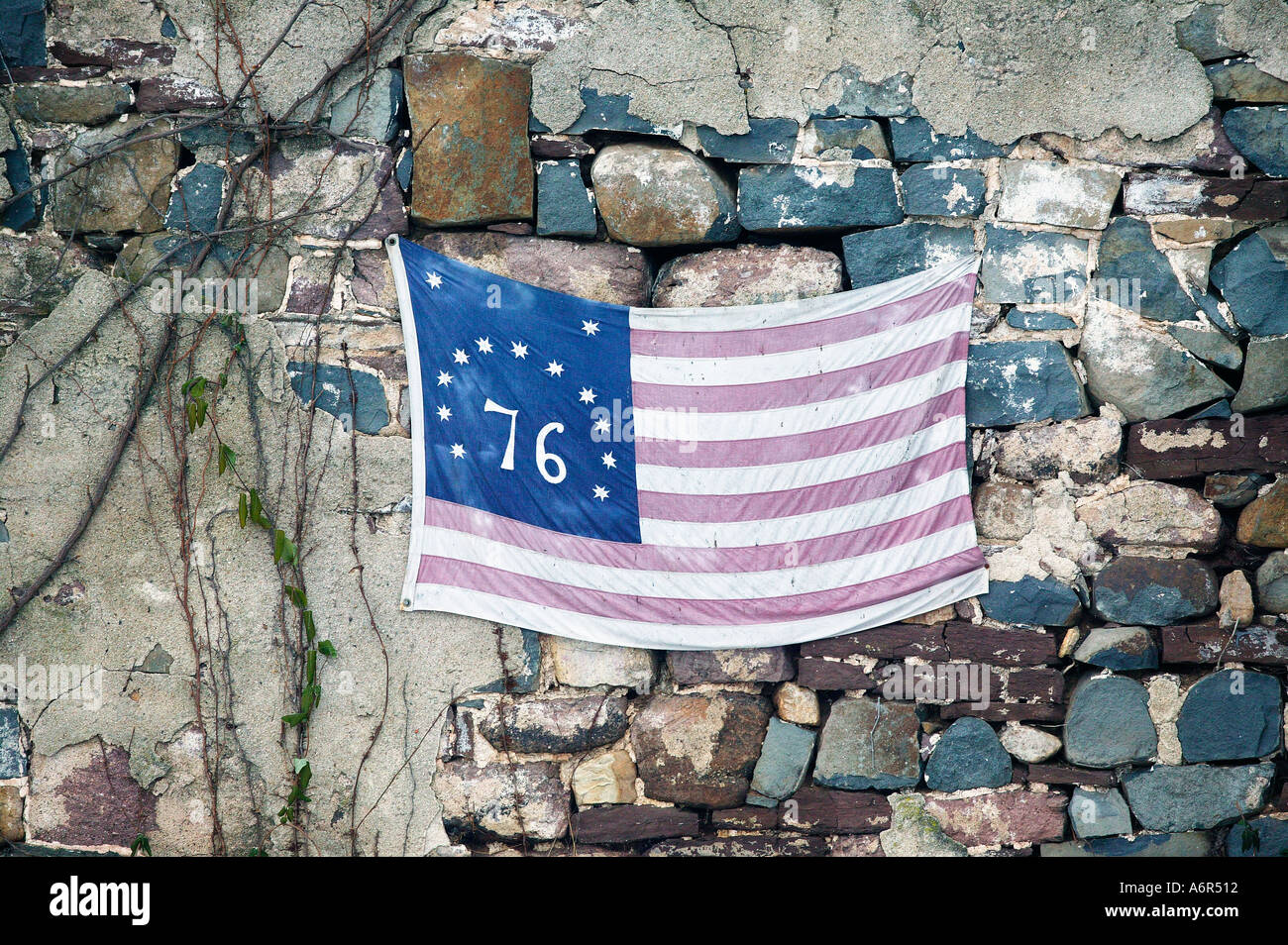 A 1776 bi centennial United States flag hangs from a rustic rock wall ...