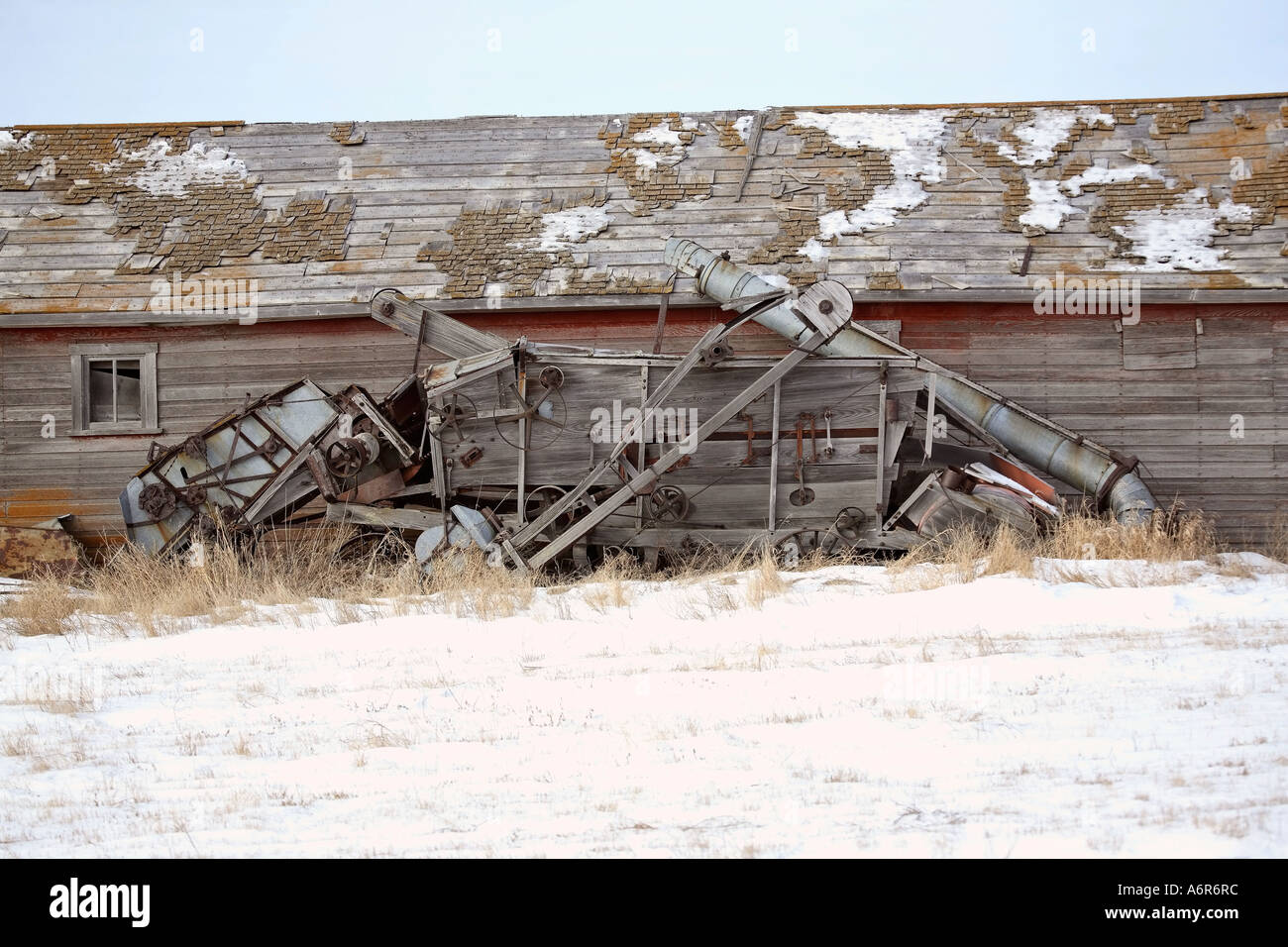 Falling apart old threshing machine against an old farm building in ...