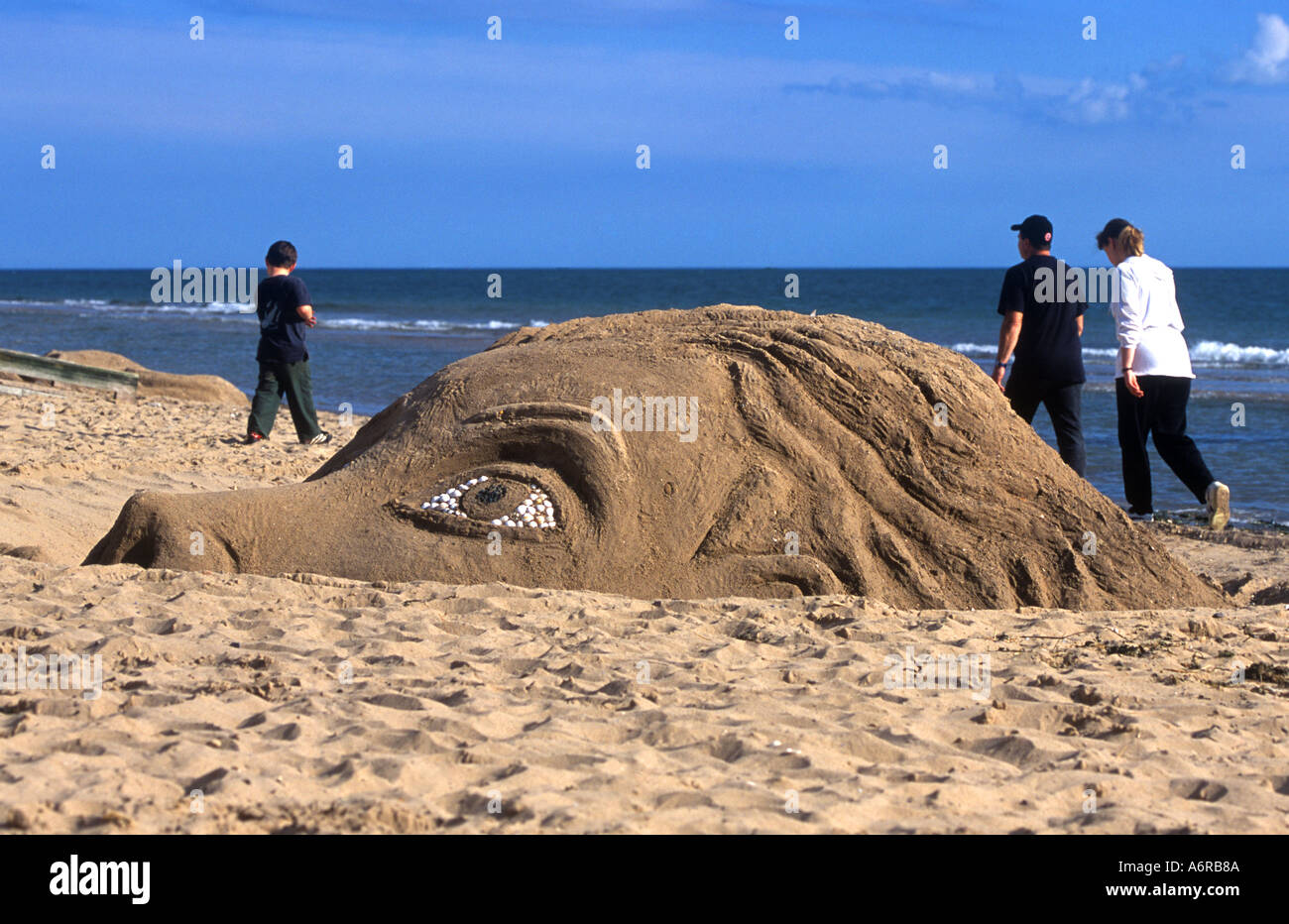 Sand Sculpture of a face and passers by at Exmouth Devon England Stock ...