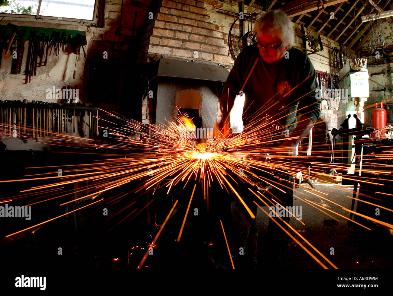 A Blacksmith sending sparks flying after bashing a hot piece of metal ...