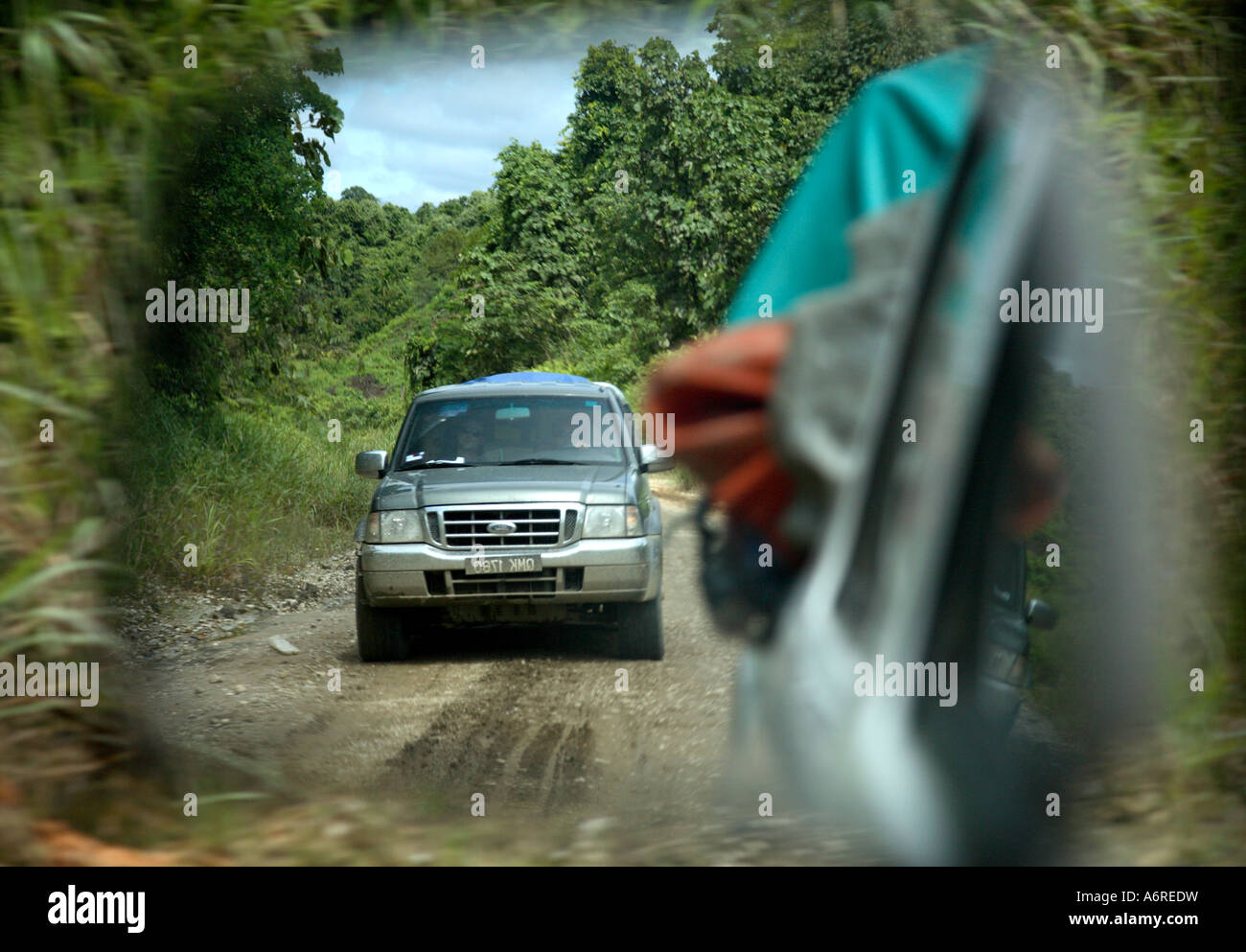 Two heavily laden pick-up trucks heading up a logging road in Sarawak ...