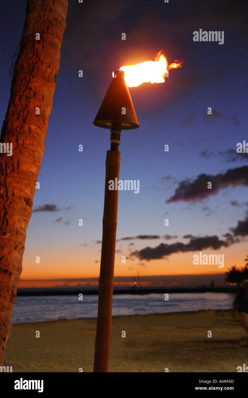Tiki Torch in Waikiki at sunset on the beach with palm tree harbor in ...