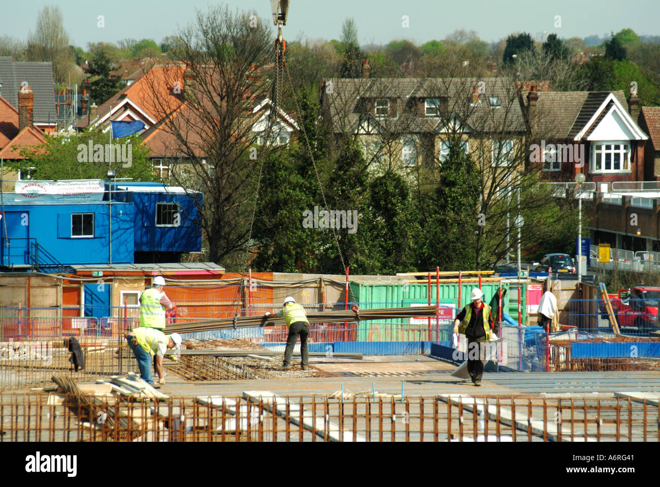 Crane lowering steel rods to construction workers on reinforced ...