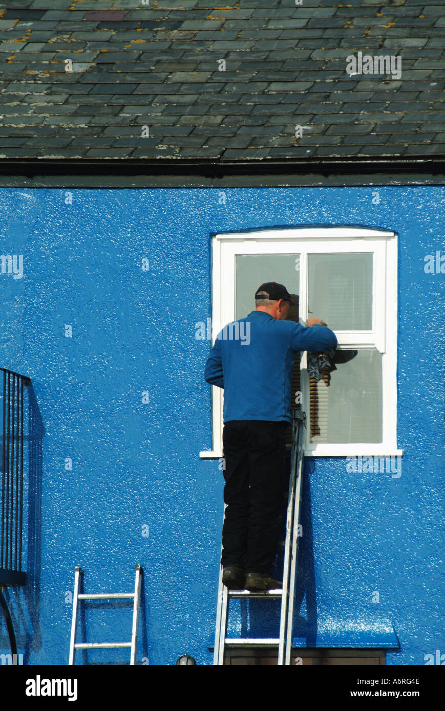 Man on ladder working on first floor window to domestic property Stock ...