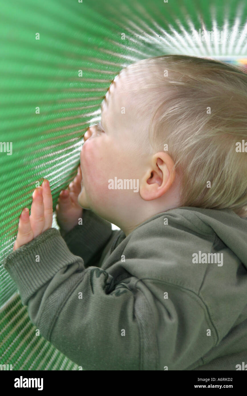 Child pressing face against green tunnel in playground enjoying touch ...