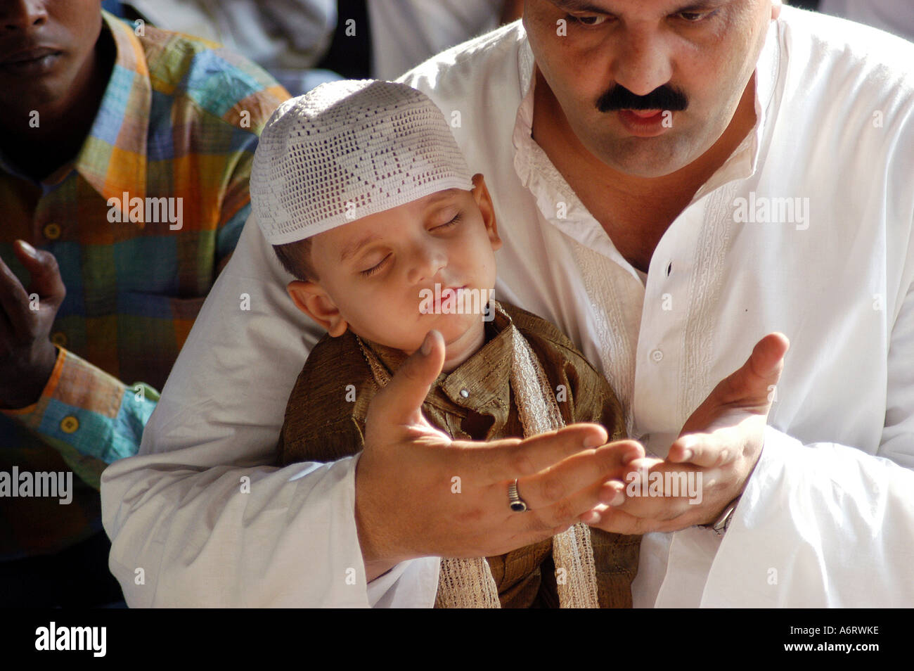ASB77322 Child sleeping peacefully as his father prays Eid ul Fitr ...