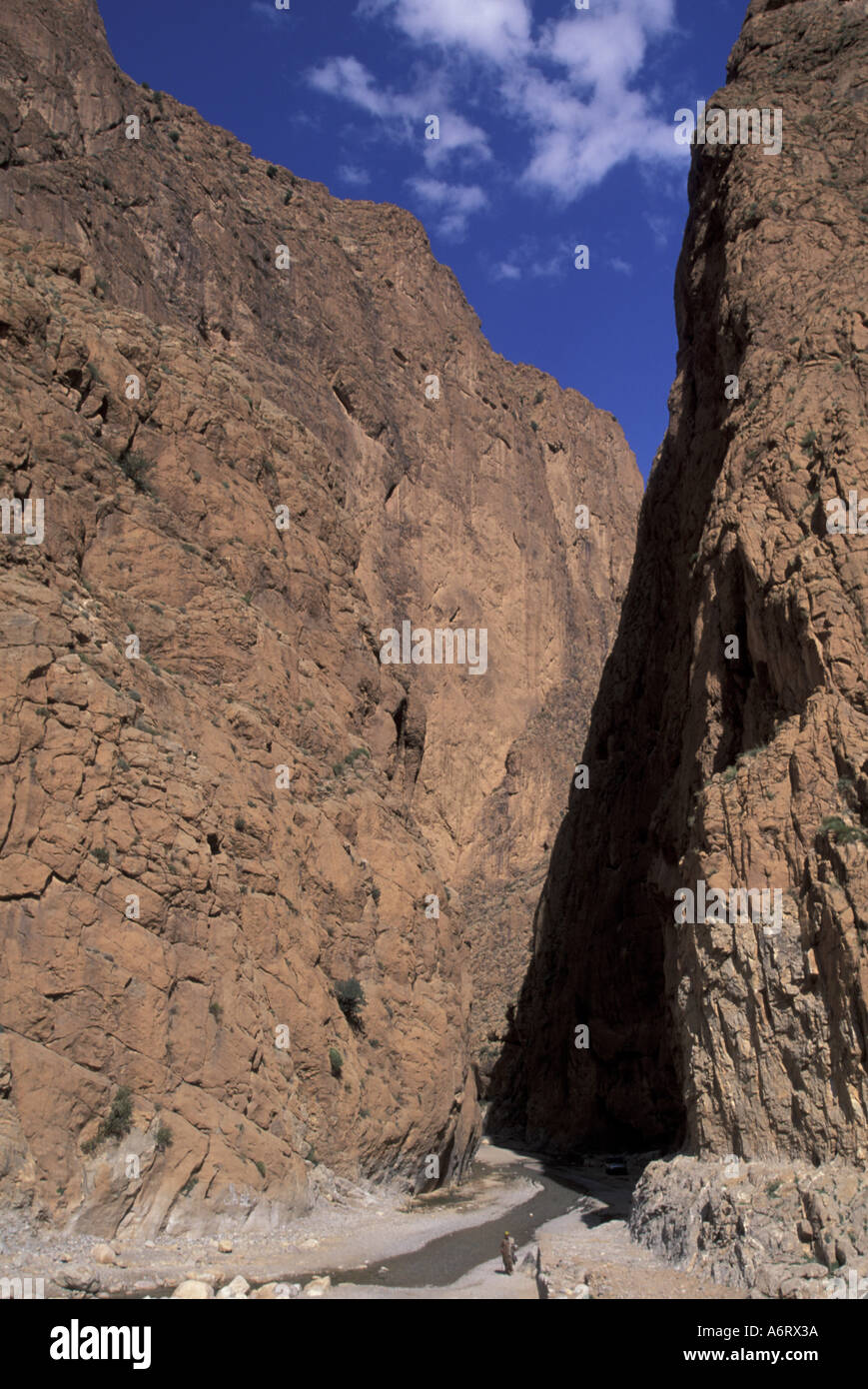 Africa, Morocco, Todra Gorge Limestone cliffs tower over man and stream ...