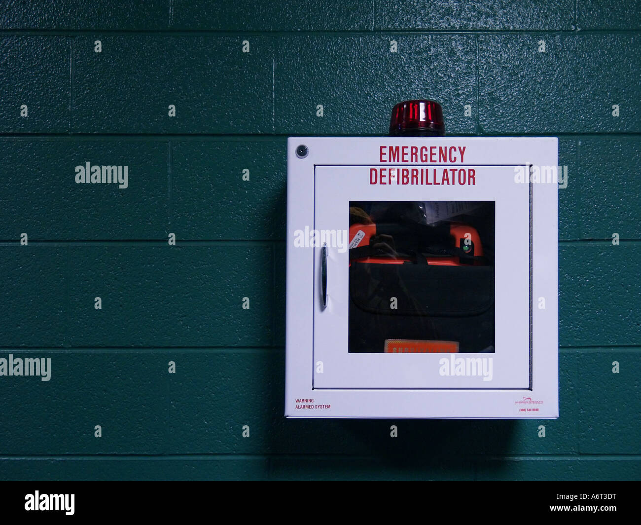 White medical box with siren on green wall reading "Emergency ...