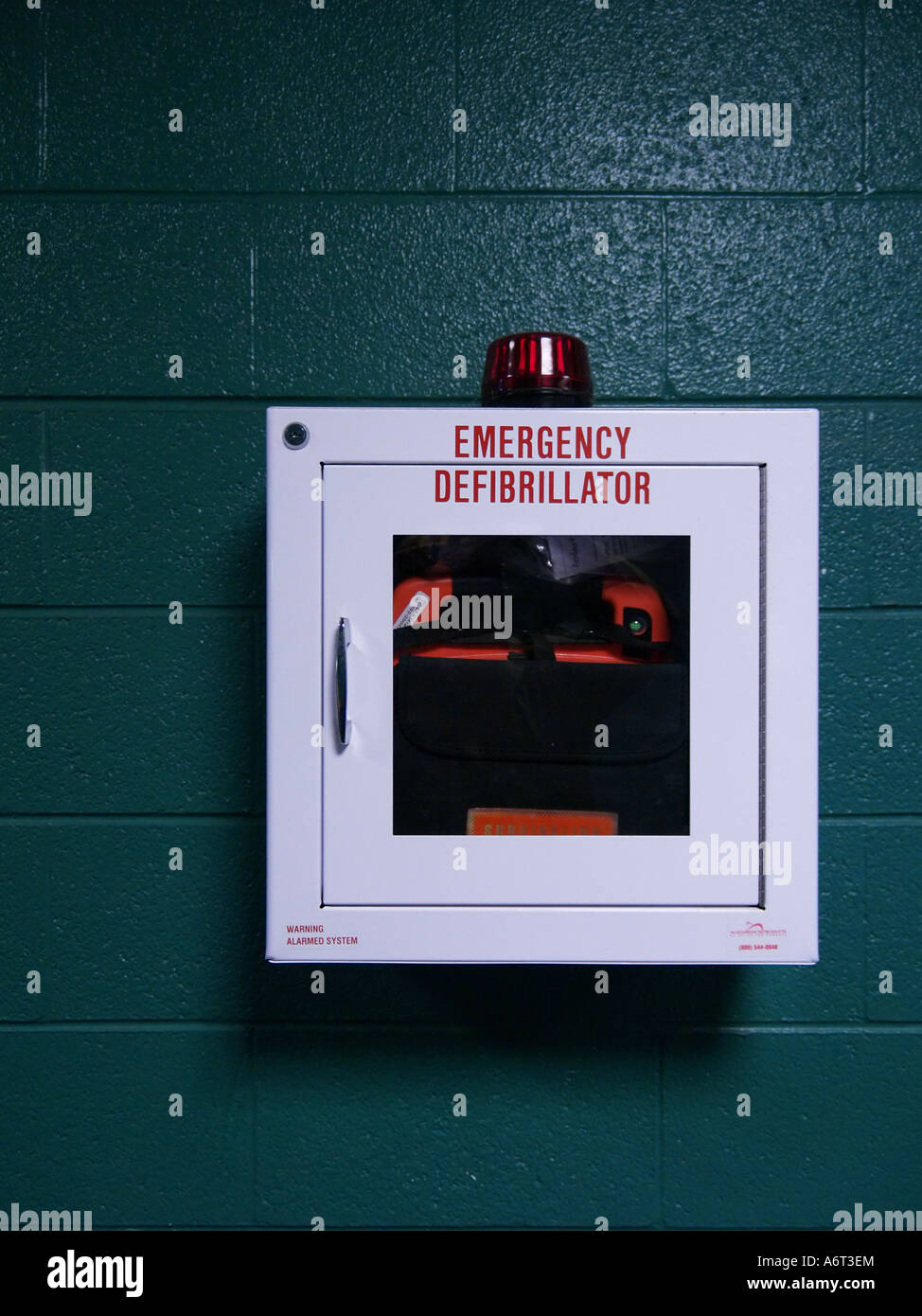 White medical box with siren on green wall reading "Emergency ...