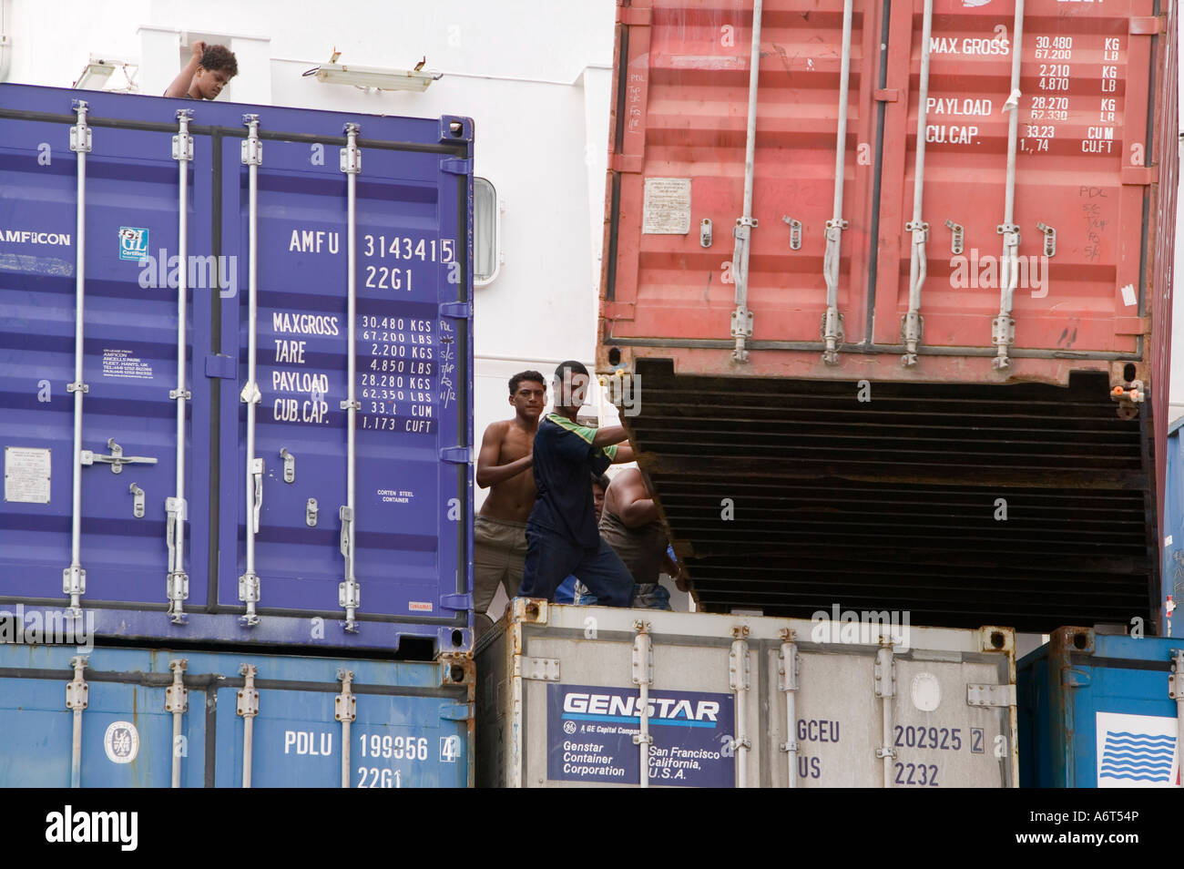 Tuvaluan workers loading containers onto a supply ship on Funafuti ...