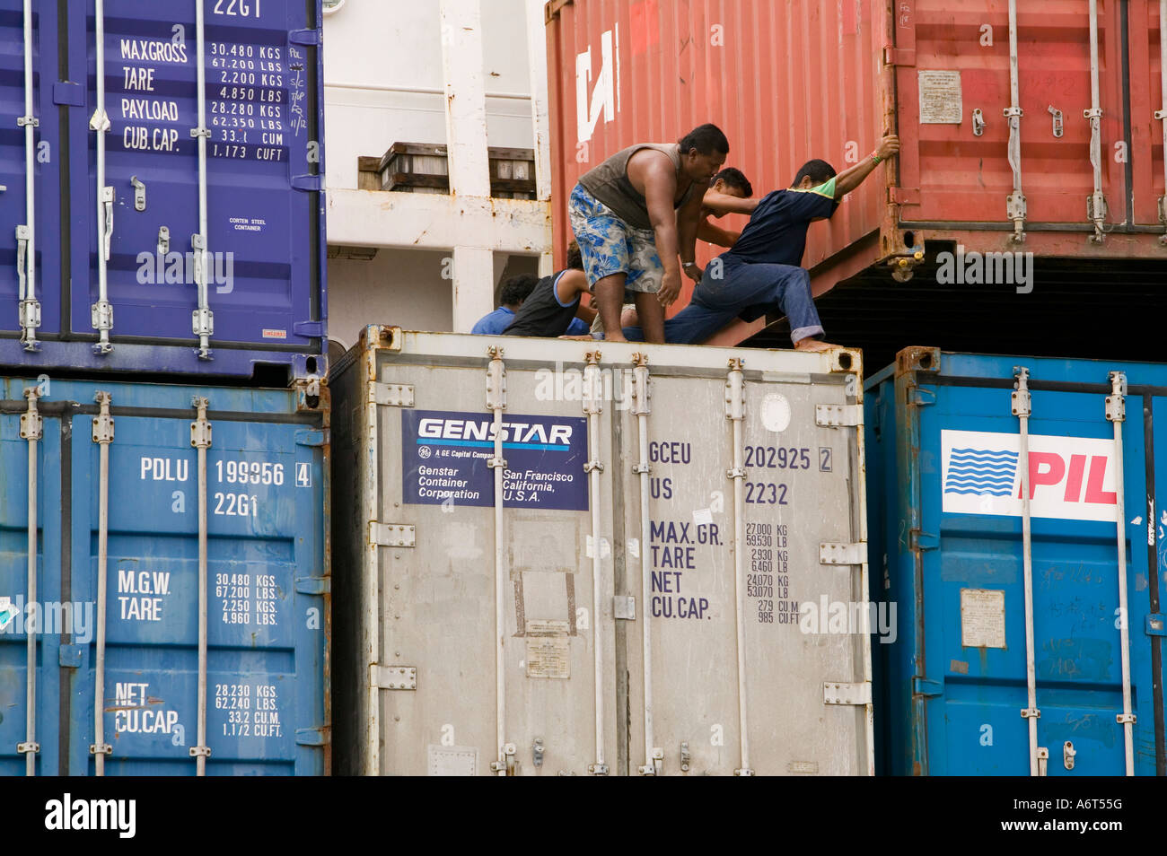 Tuvaluan workers loading containers onto a supply ship on Funafuti ...