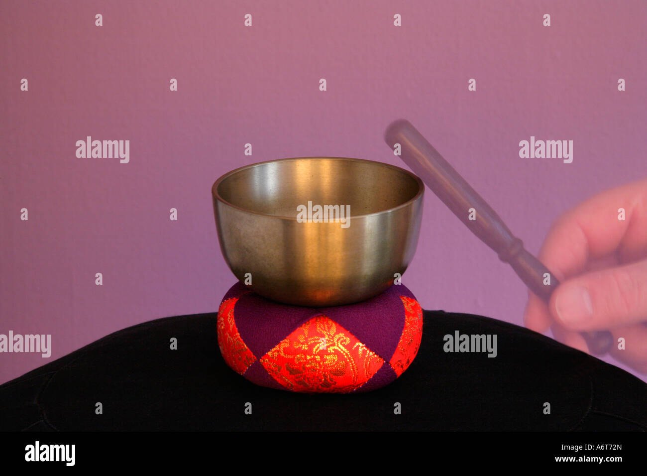 Zen Buddhist Bell Bowl on cushion with hand with bell stick striking ...