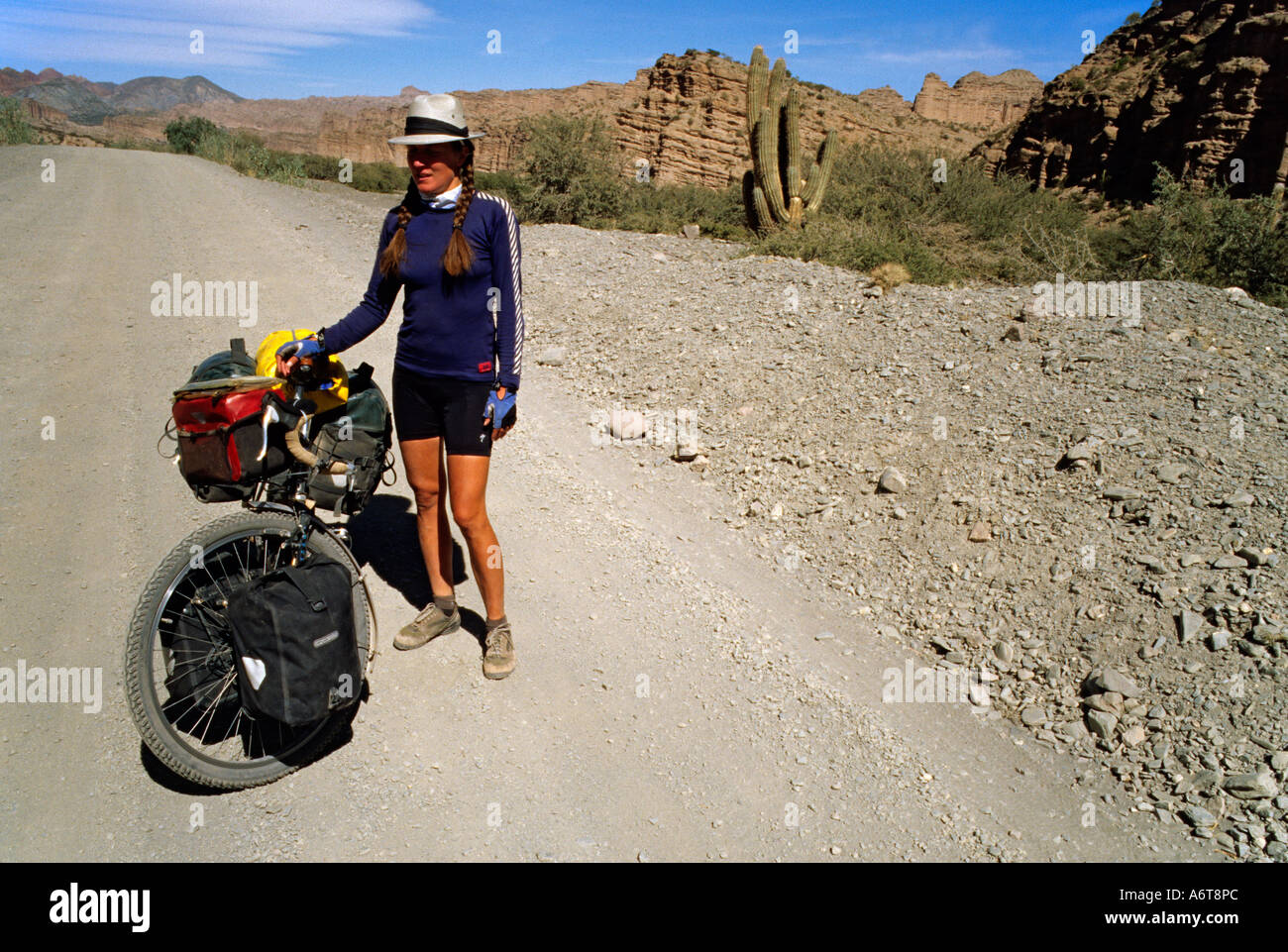 female expedition touring cyclist standing next to bicycle on dusty ...