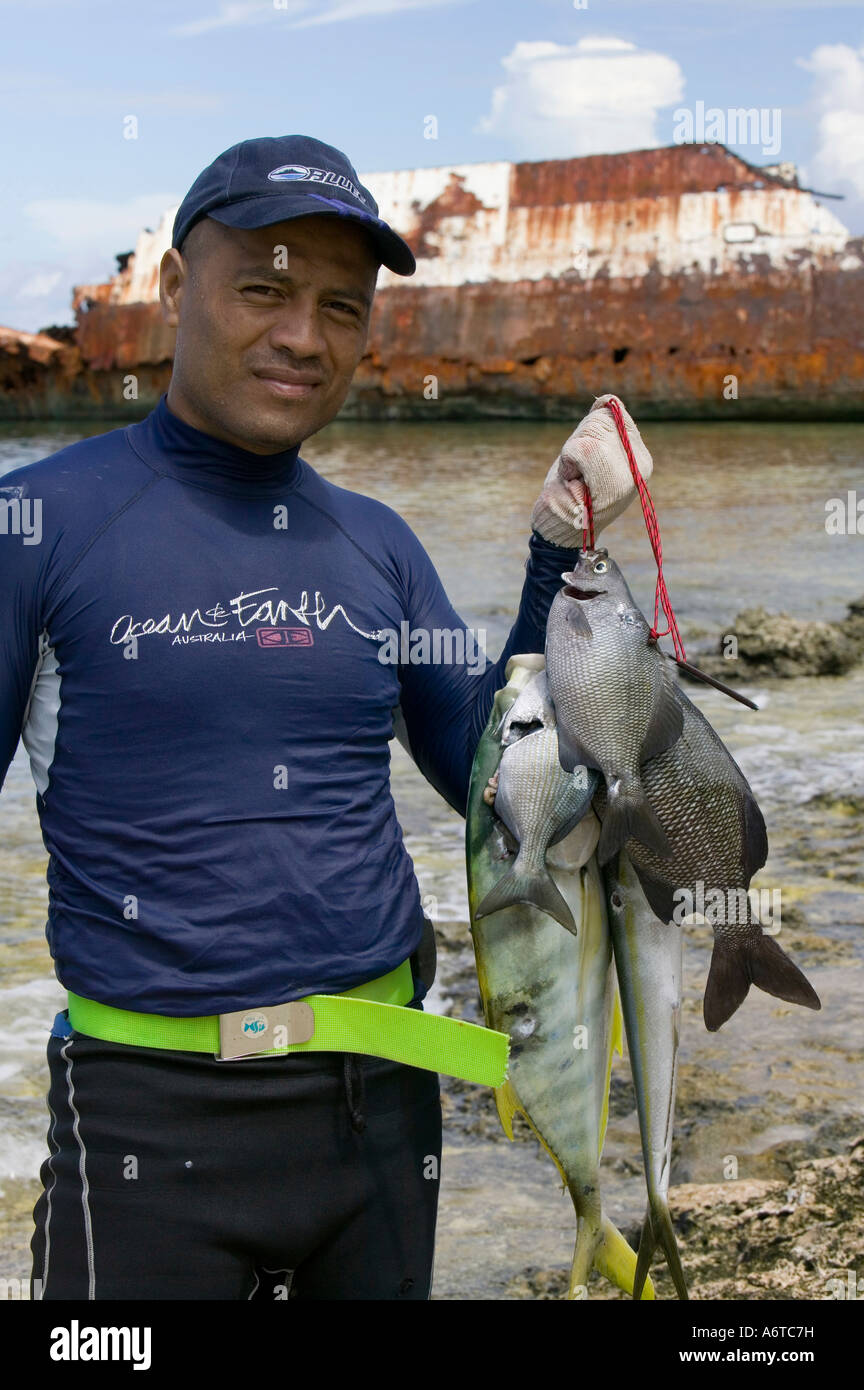 A tuvaluan fisherman on Funafuti in front of a shipwreck caused by ...