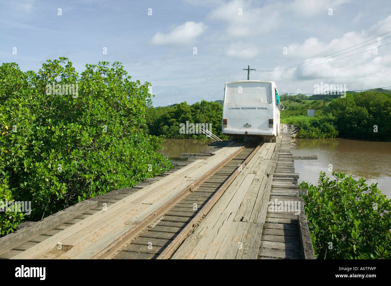 A bus crossing a rickety wooden bridge across a river on Fiji Stock ...